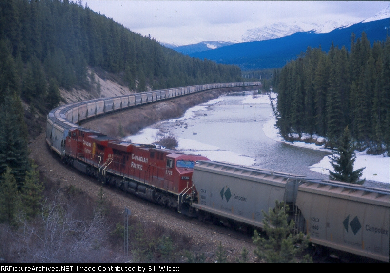 CP 8735 & 8520 work as mid-train helpers on a westbound CANPOTEX train along the Bow River ...